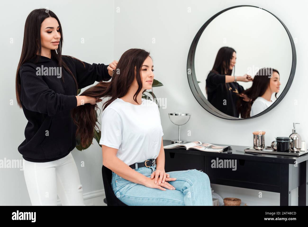 Smiling, professional hairdresser combs beautiful hair to client Stock ...