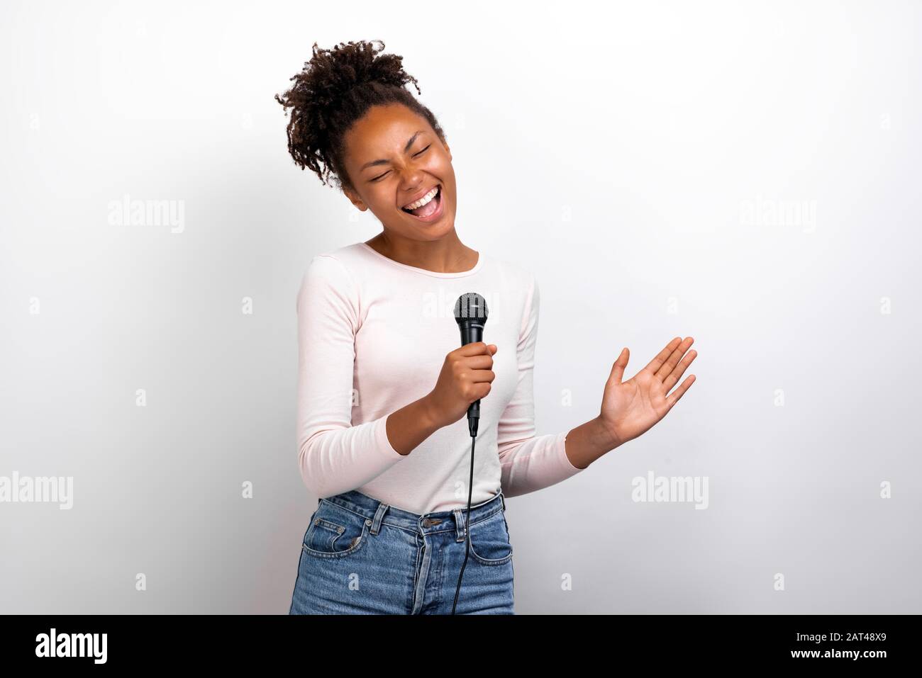 Funny mulatto woman singer holds a microphone in her hands against a ...