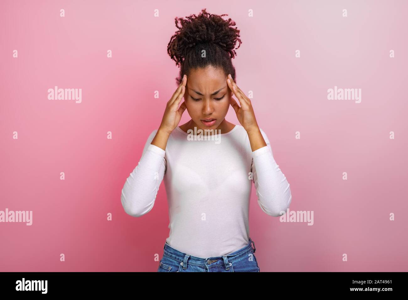 Studio portrait mulatto woman touching pressed herself head with her ...