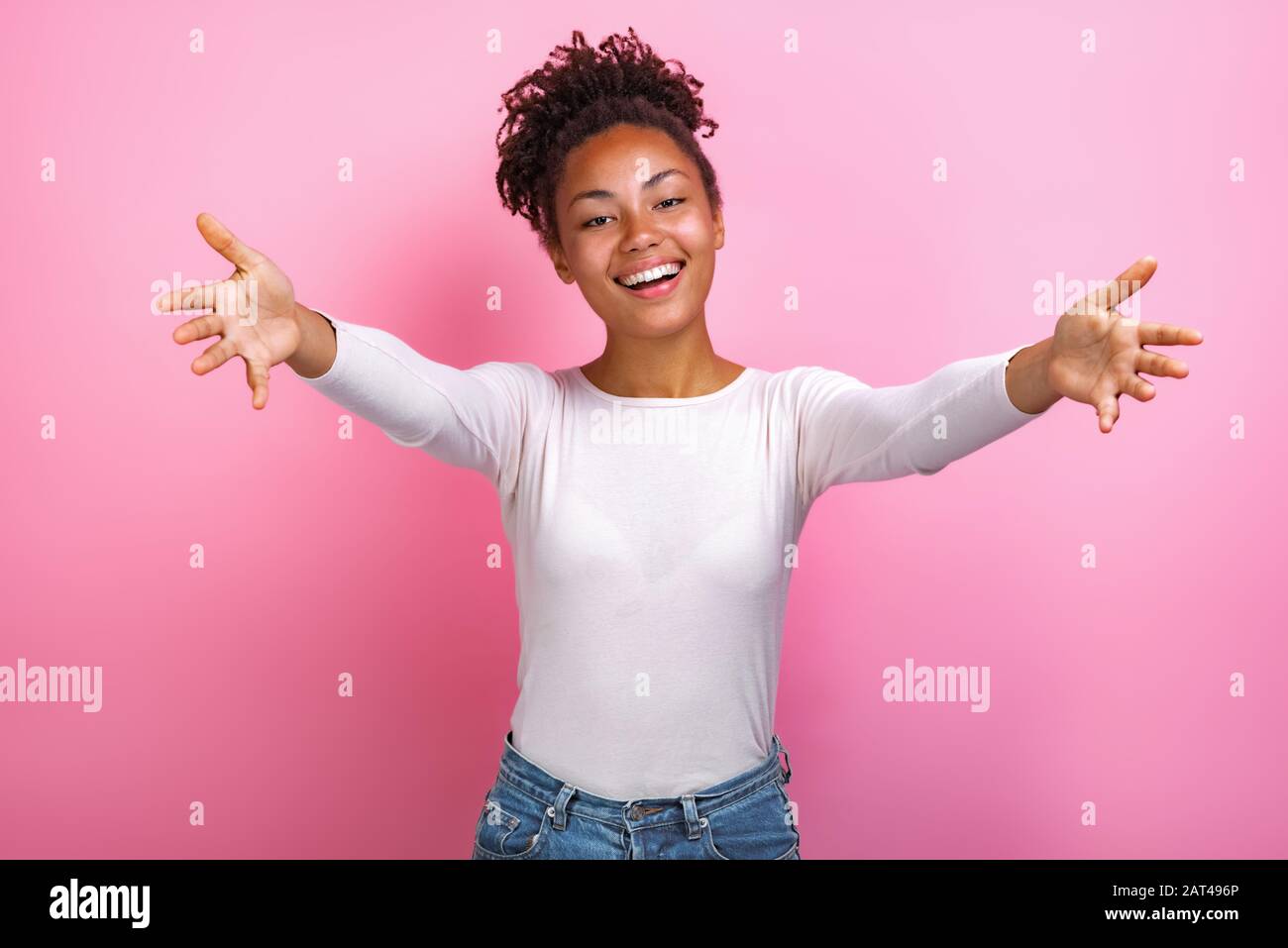 Studio portrait of woman wide arms apart pose over pink background ...