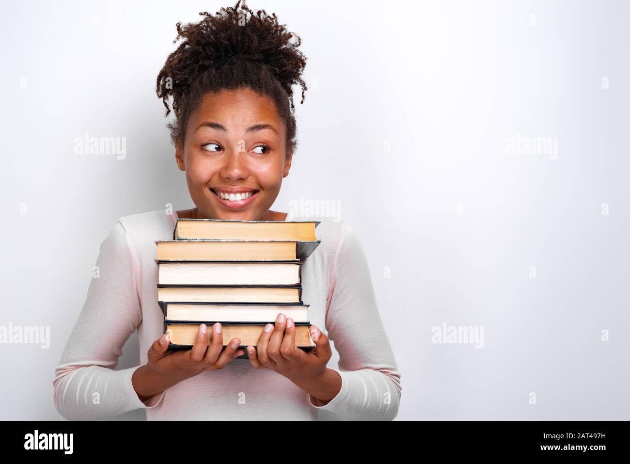 Portrait of happy nerd young girl holding books over white background ...