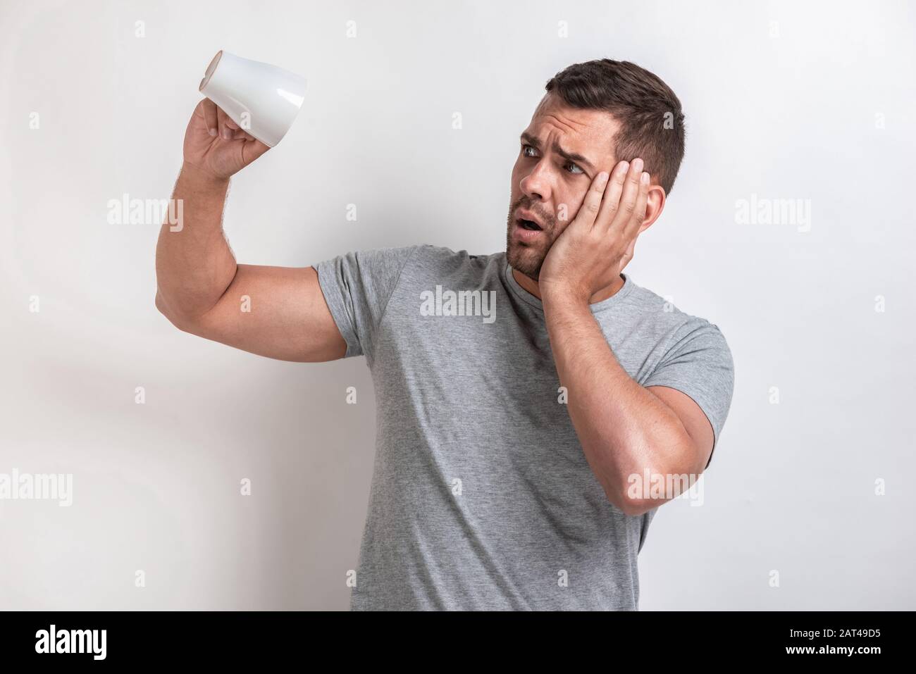 Sadly man flips an empty cup and looking unhappy, touches on cheek ...