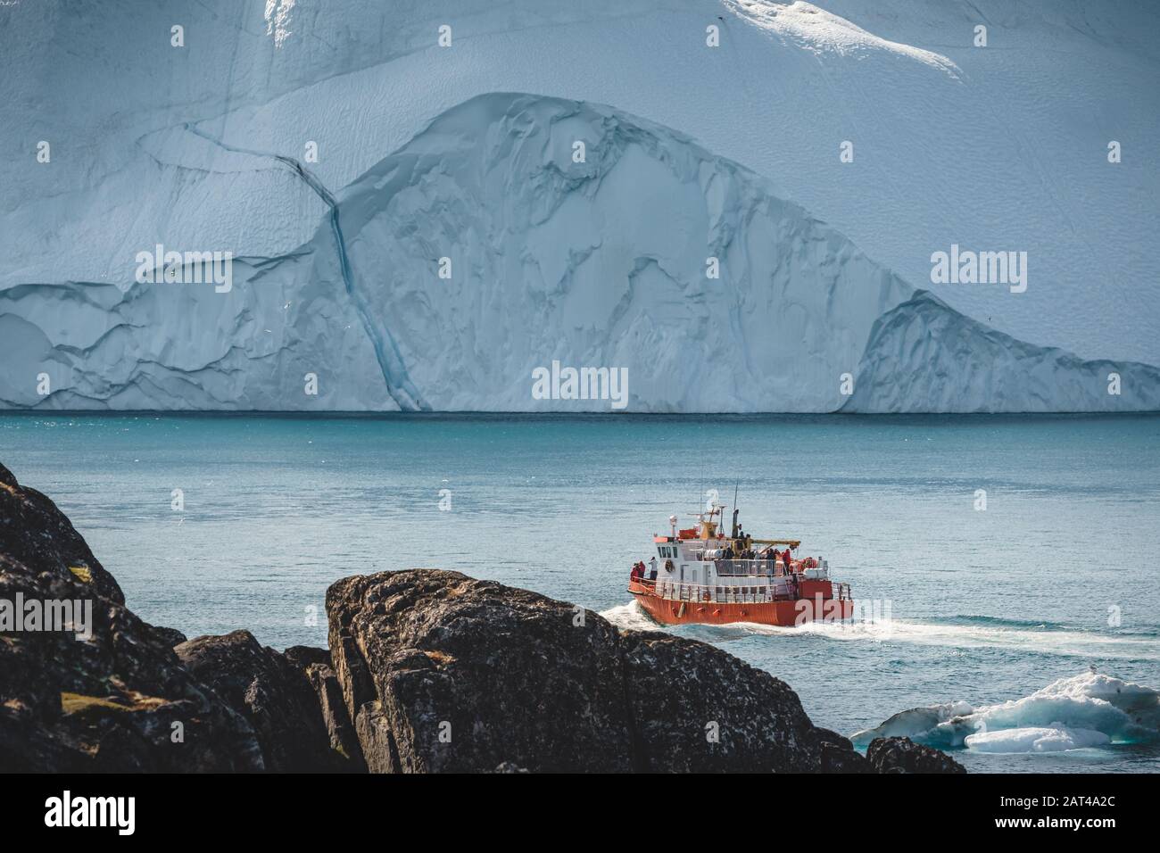 Orange whale Watching tour boat ship with icebergs in background. View ...