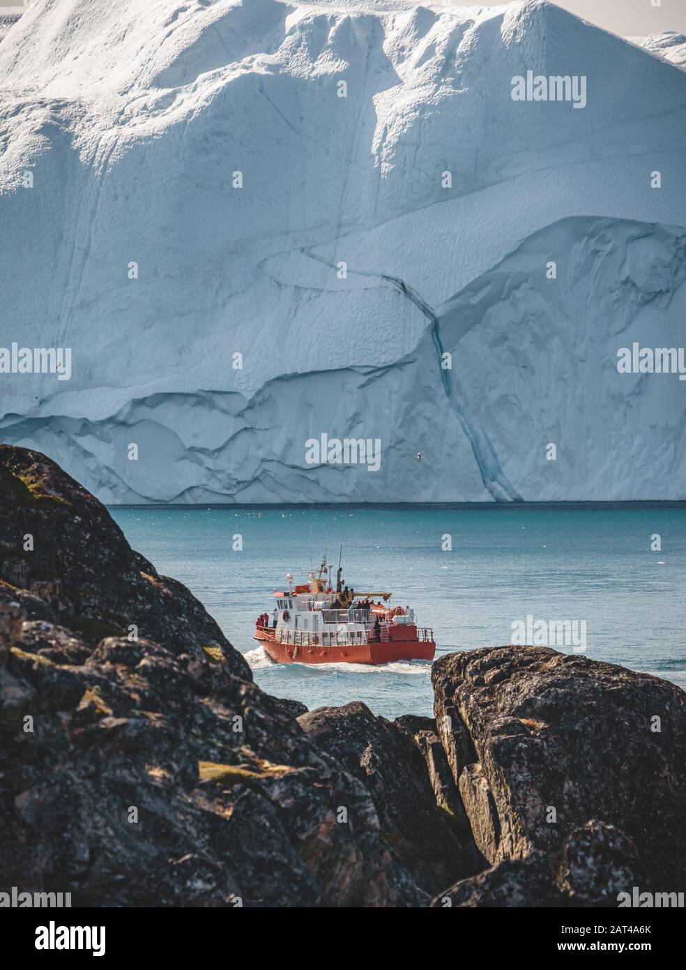 Orange whale Watching tour boat ship with icebergs in background. View ...