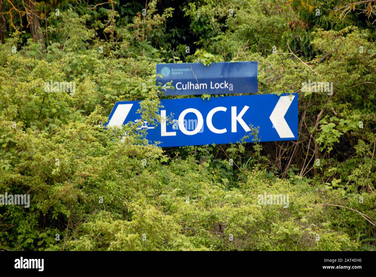 Sign showing direction of lock on river, partly covered by summer ...