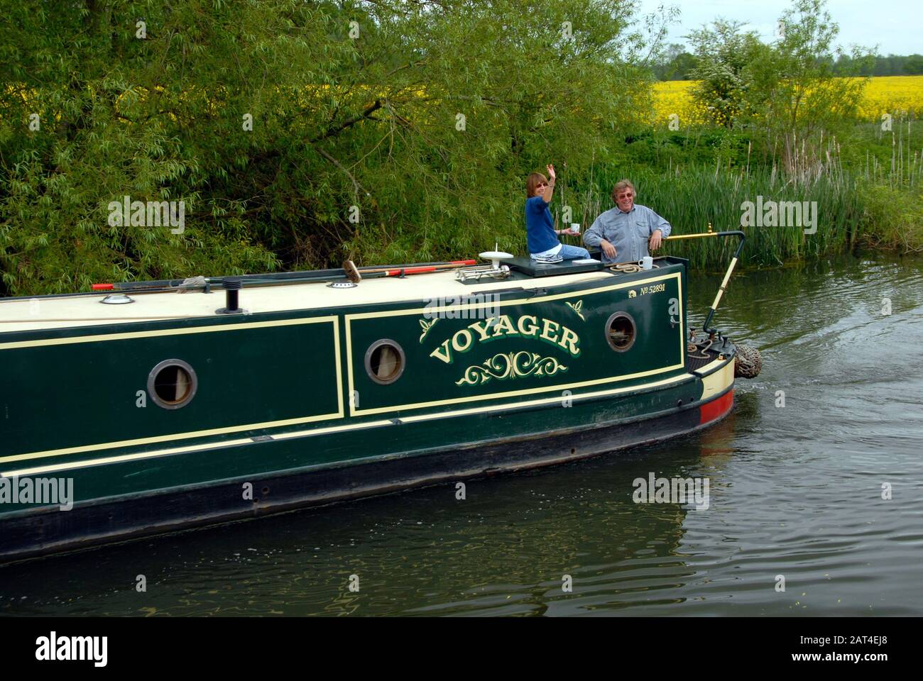 Couple at stern of narrow boat on river Thames, England, with lady ...