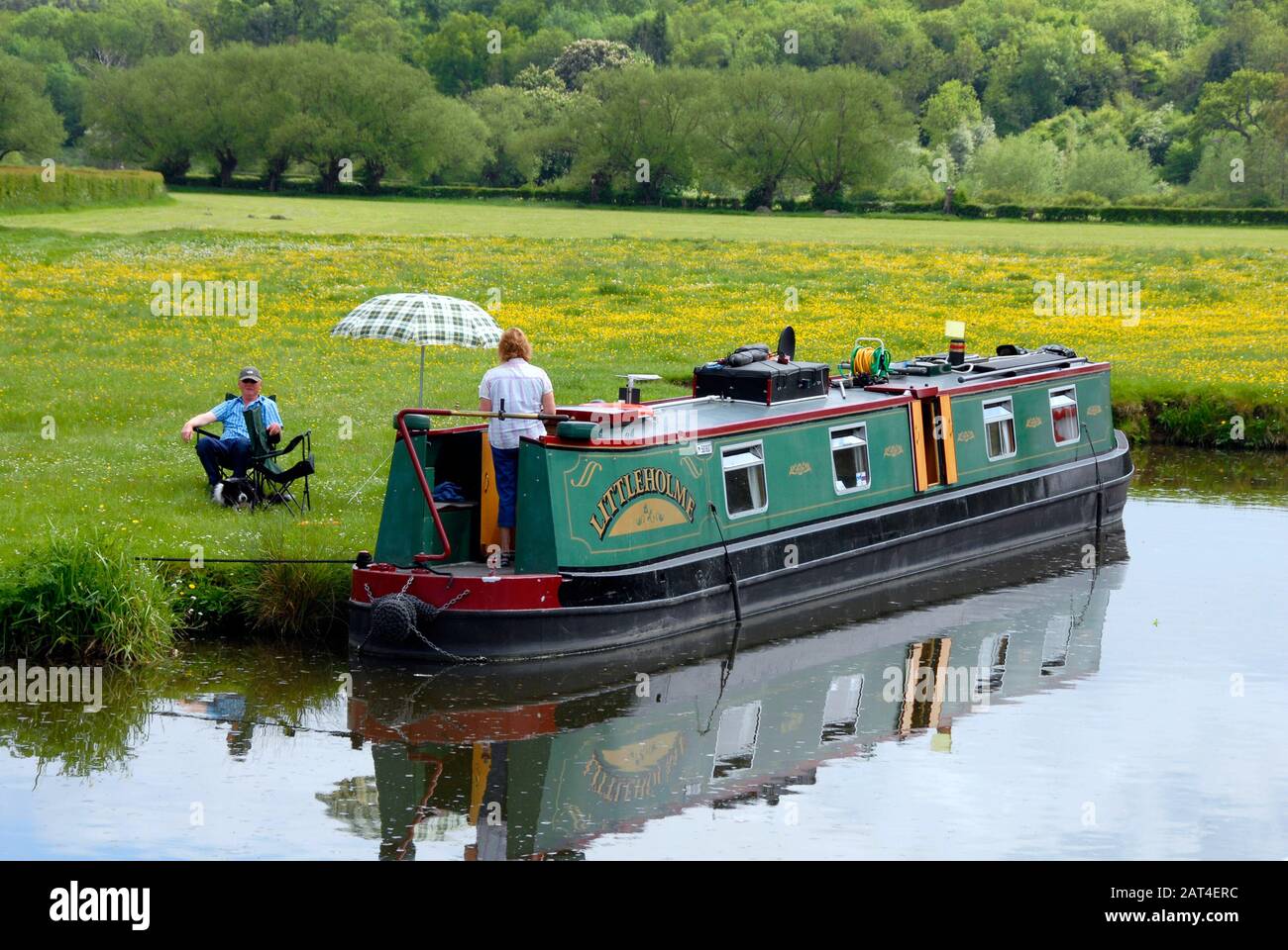 Narrow boat moored at bank of river Thames, England with lady on board ...