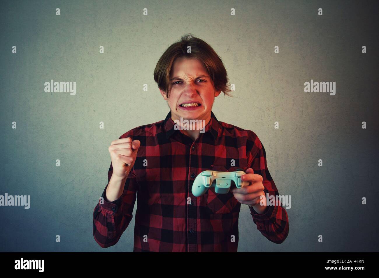 Frustrated teenage boy playing video games isolated on grey wall ...