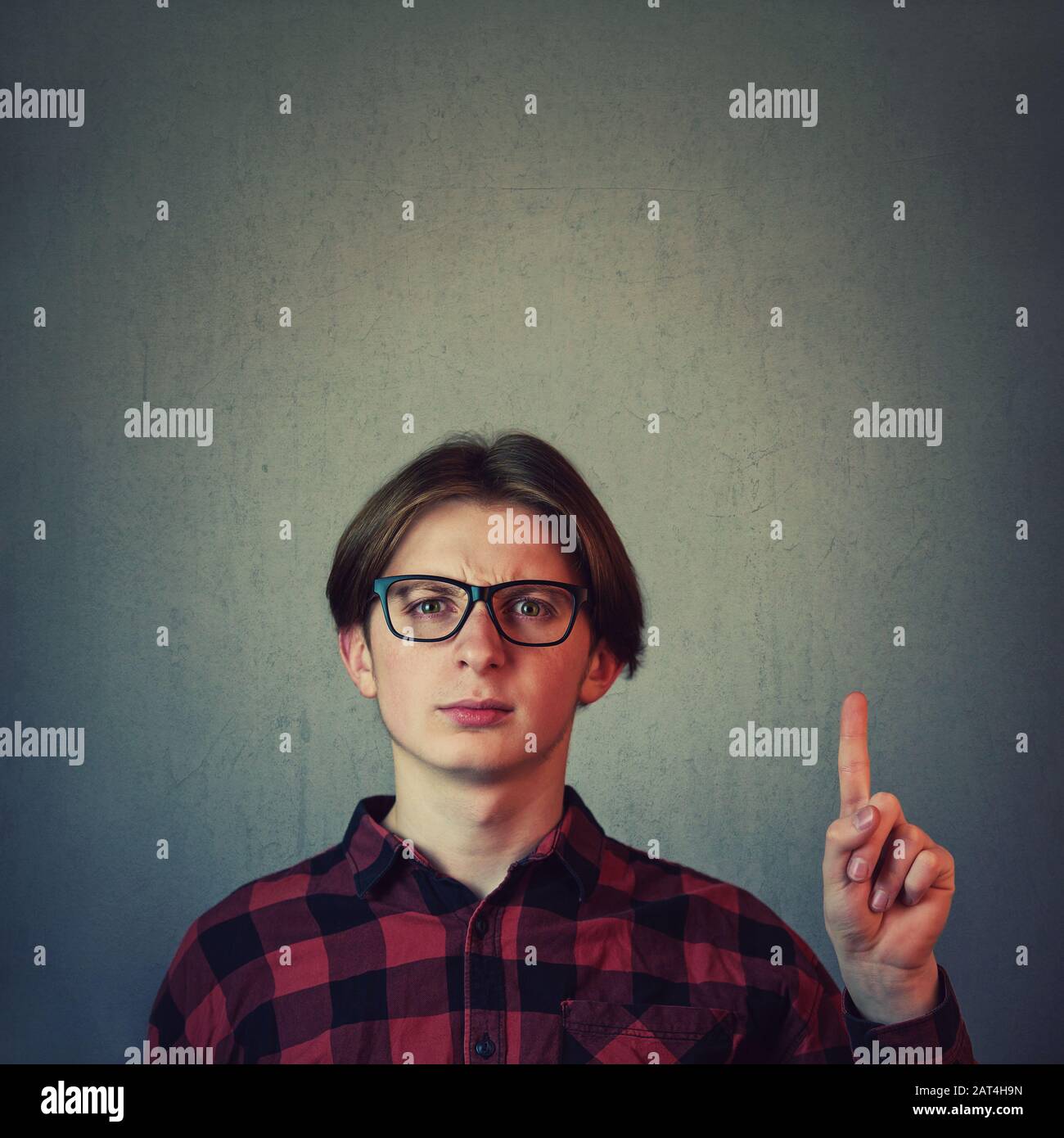 Confused adolescent guy, wearing eyeglasses gesturing, pointing index ...