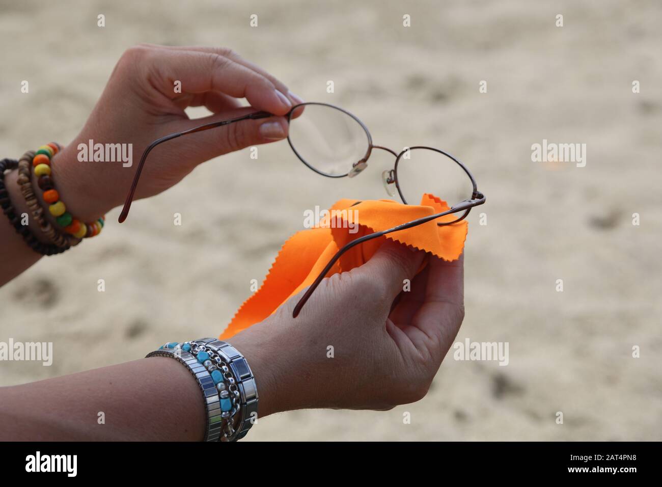 Closeup of hands cleaning glasses lens with orange cloth lens on the ...