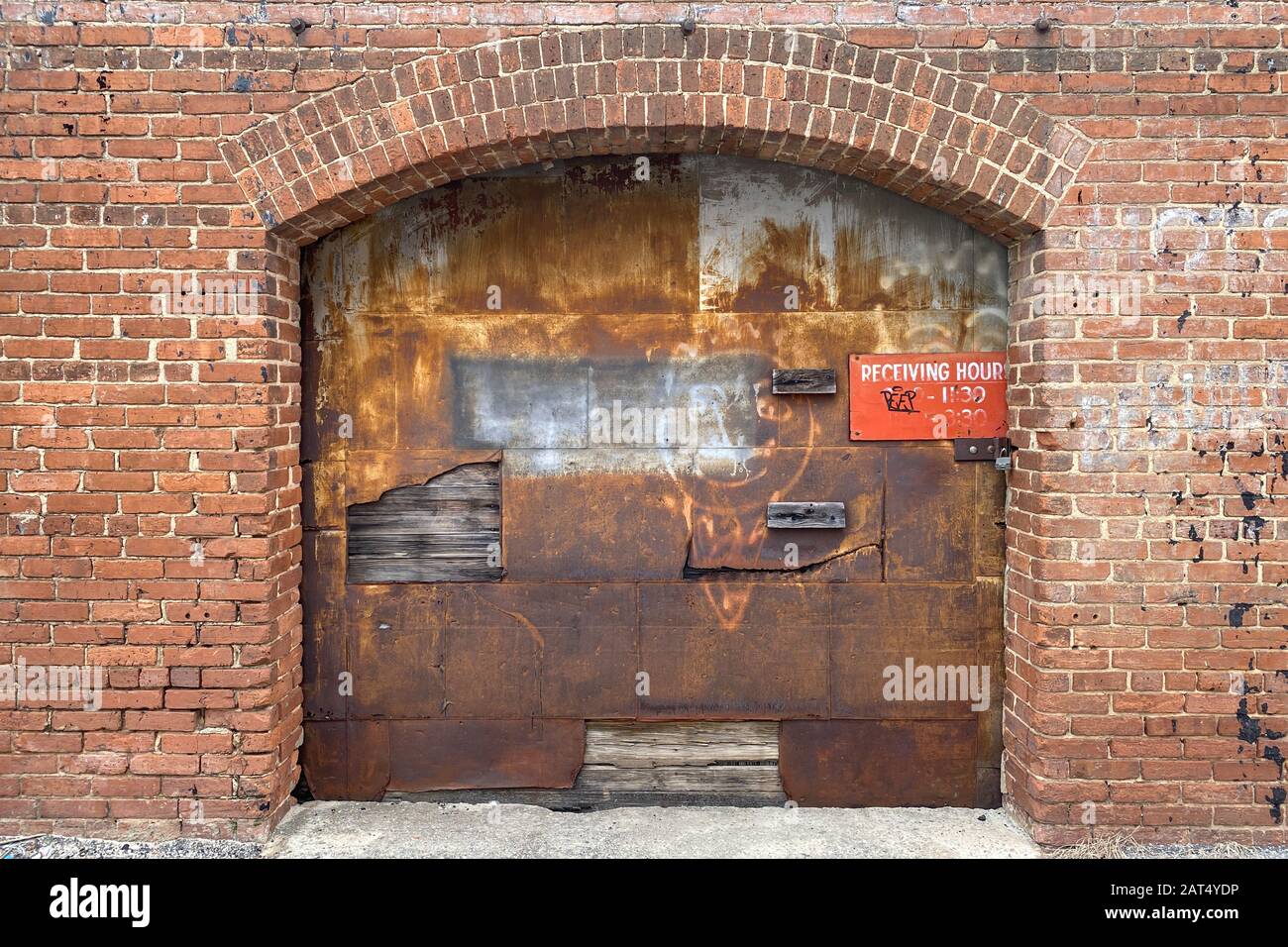 a rusted warehouse delivery receiving bay door and red brick building ...