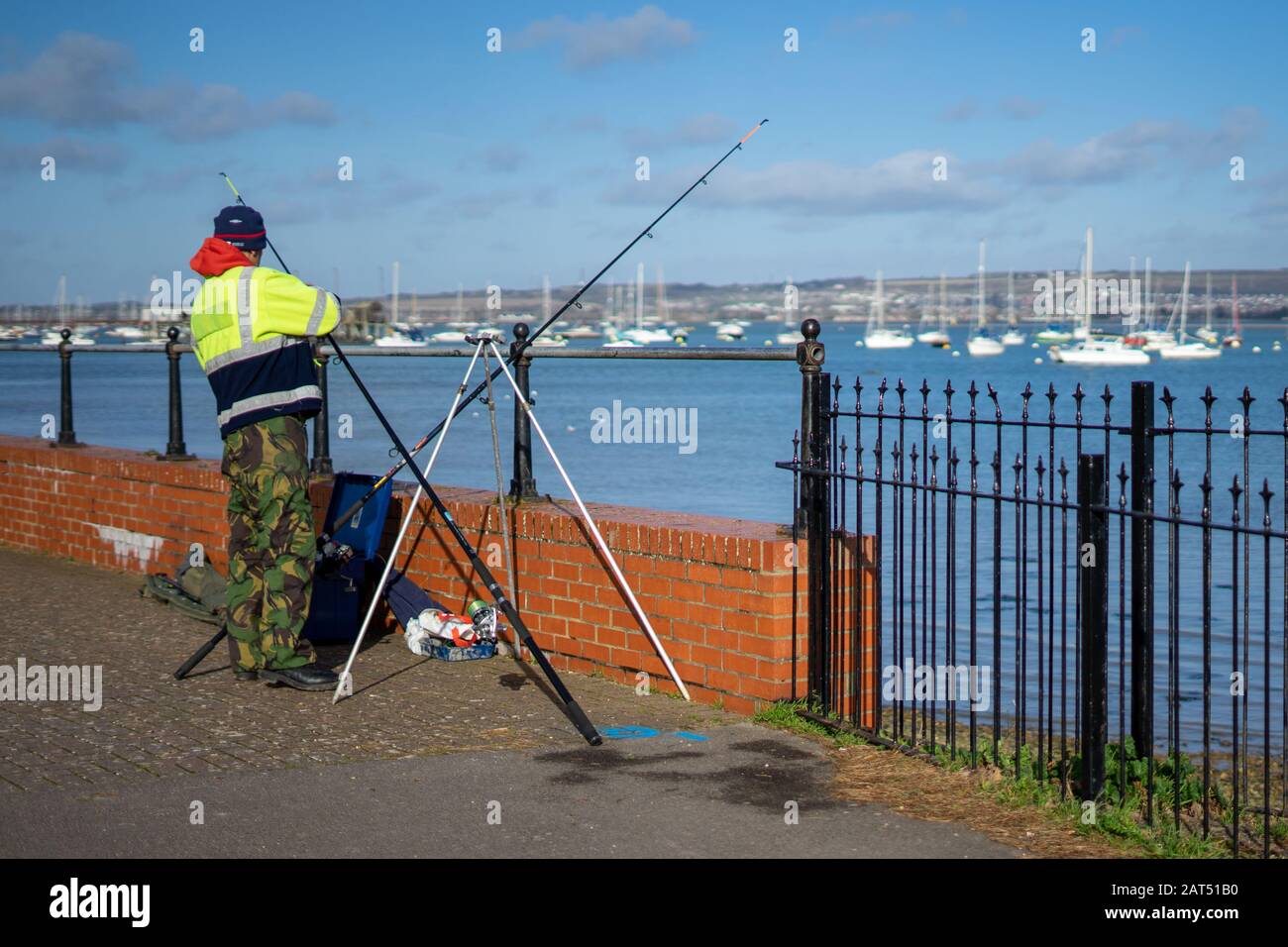 a man fishing alone at the shore with his rod on a stand Stock Photo ...