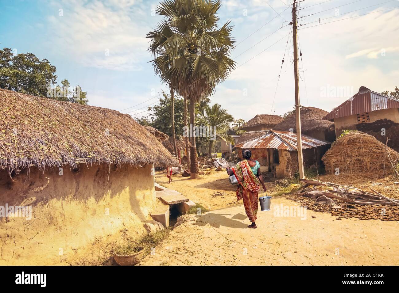 Rural Indian village scene with woman carrying bucket of water with ...