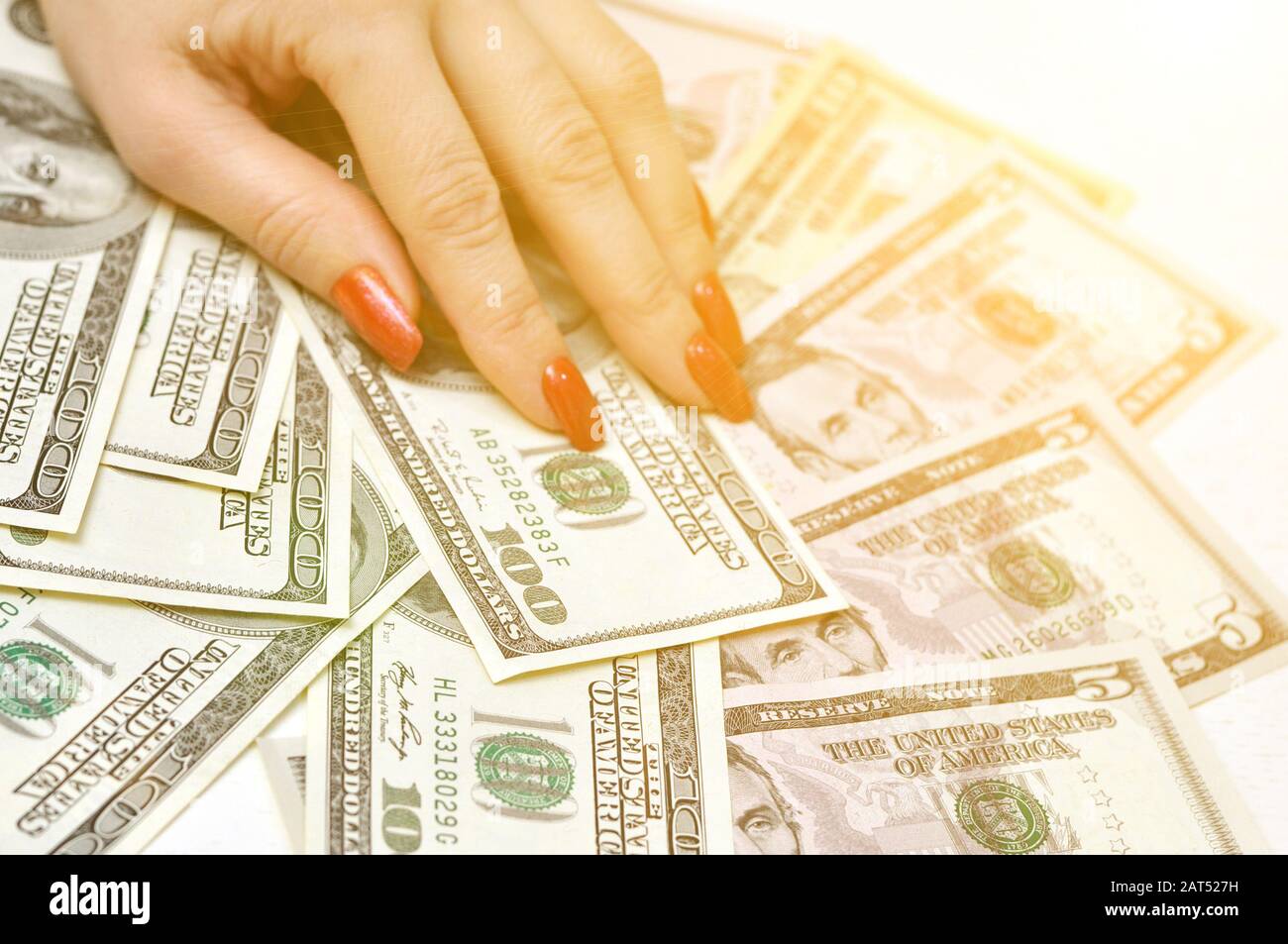 Female fingers with long artificial manicured nails hold a wad of money ...
