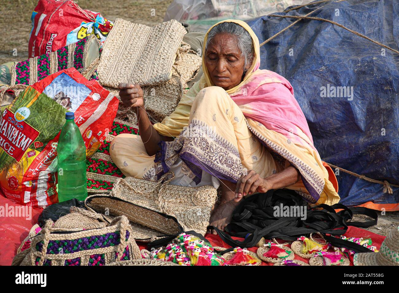 Rural woman sewing handmade jute craft items for selling at a ...