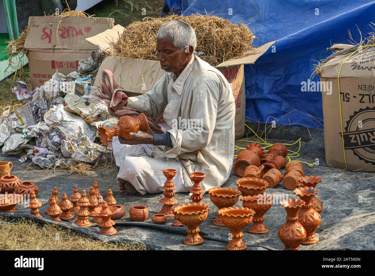 Old man selling handmade clay flower vase and other craft items at a ...