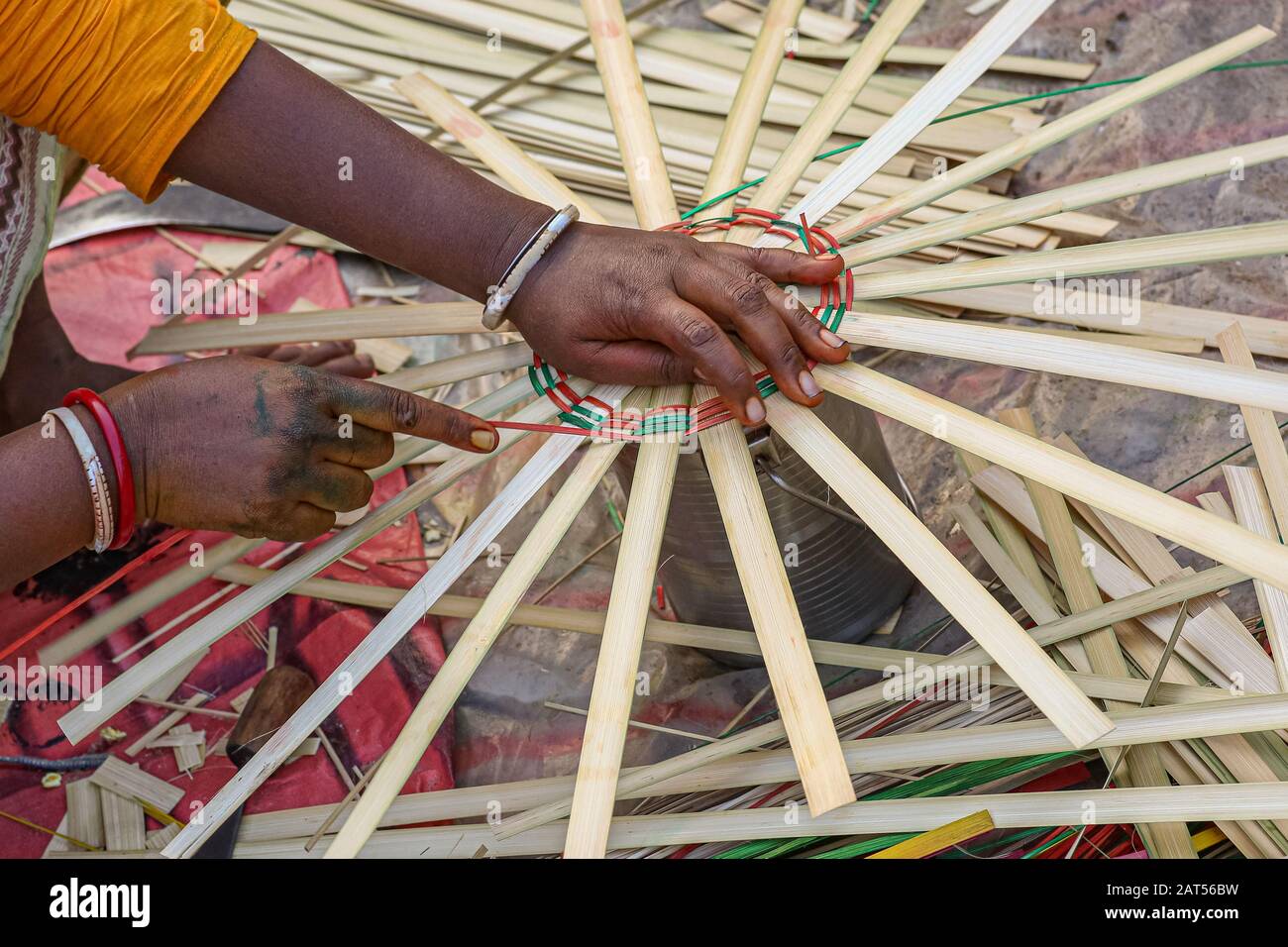 Rural woman hand weaving a basket from bamboo cane strands at a ...