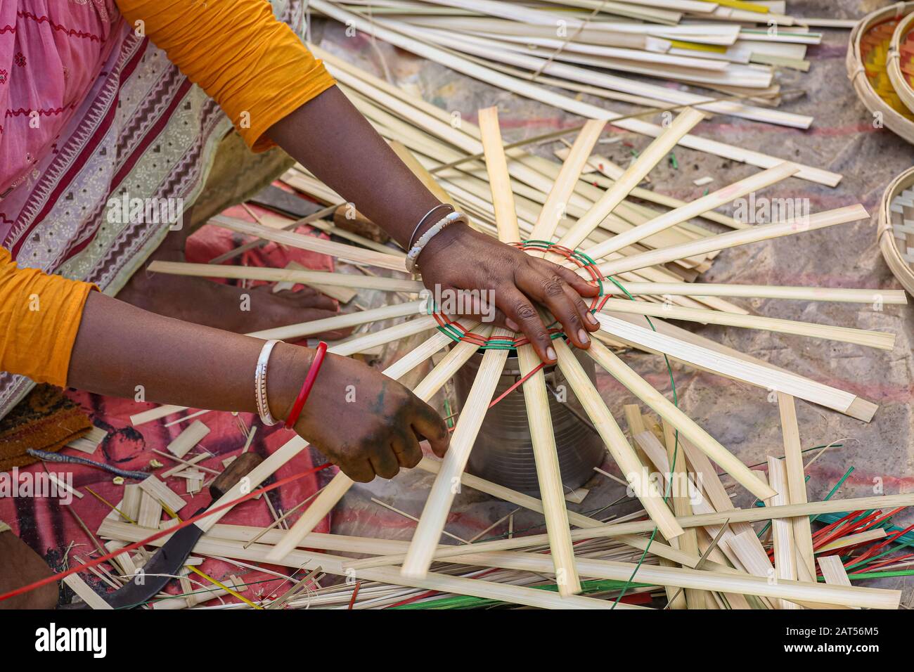 Rural woman hand weaving a basket from bamboo cane strands at a ...