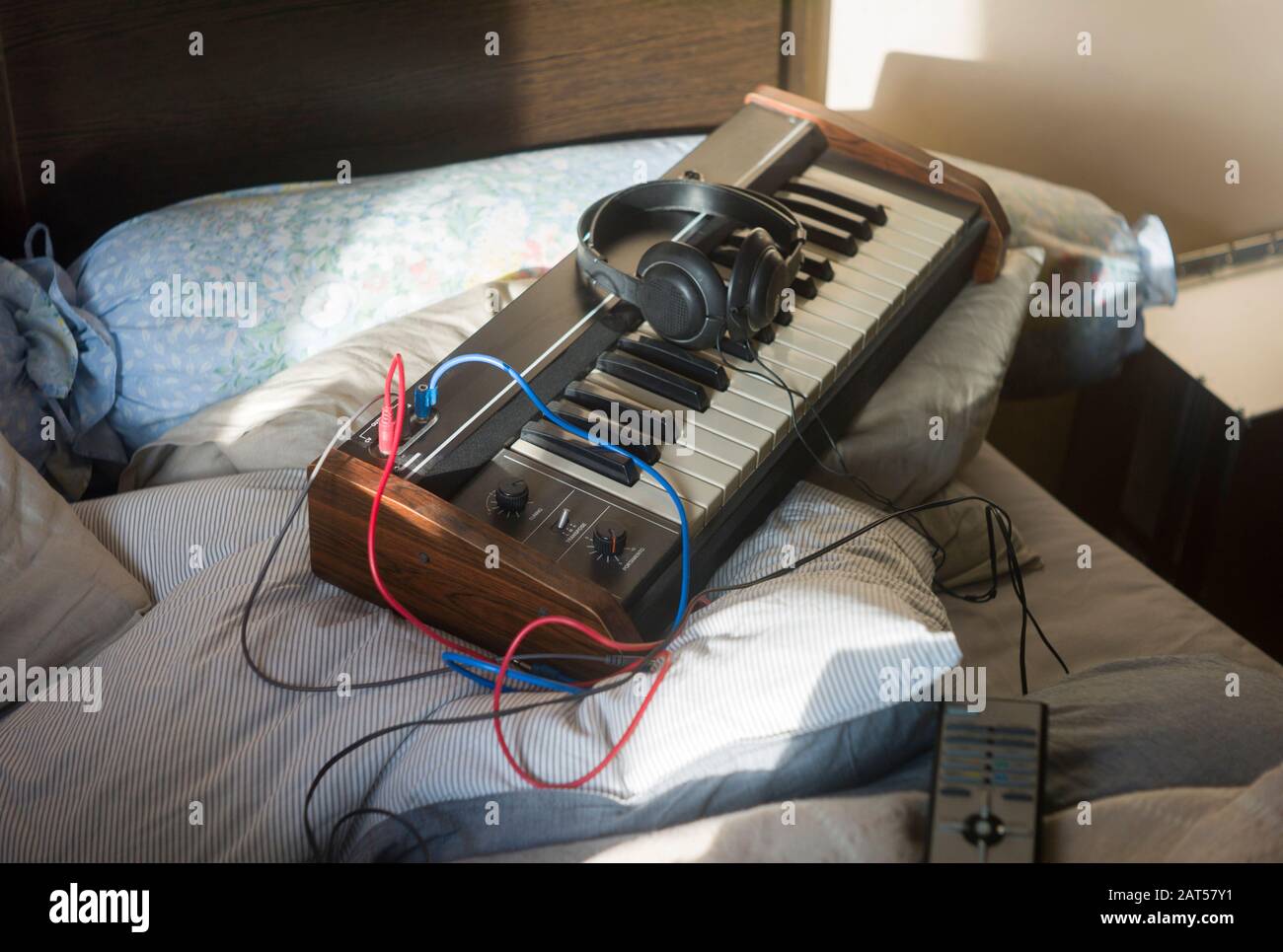 Synthesizer abandoned on a messy bed, concept of home music studio ...