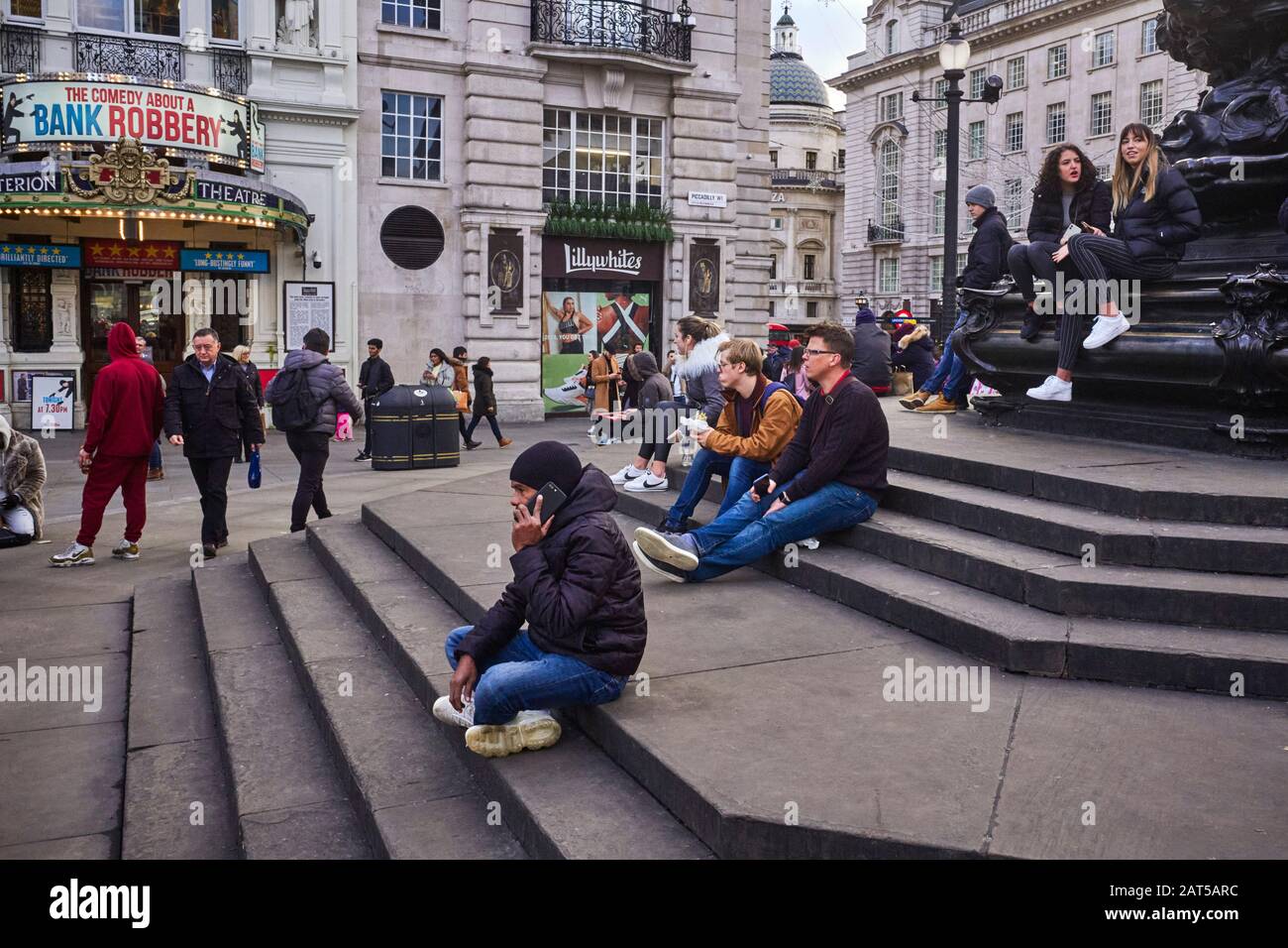 People sitting on the steps of the Eros statue in Piccadilly Circus ...