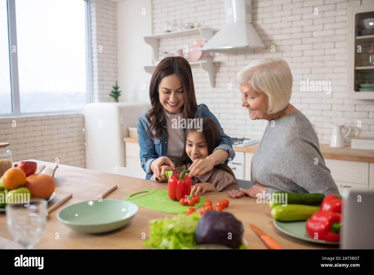 Smiling mom, daughter and grandmother making breakfast Stock Photo - Alamy