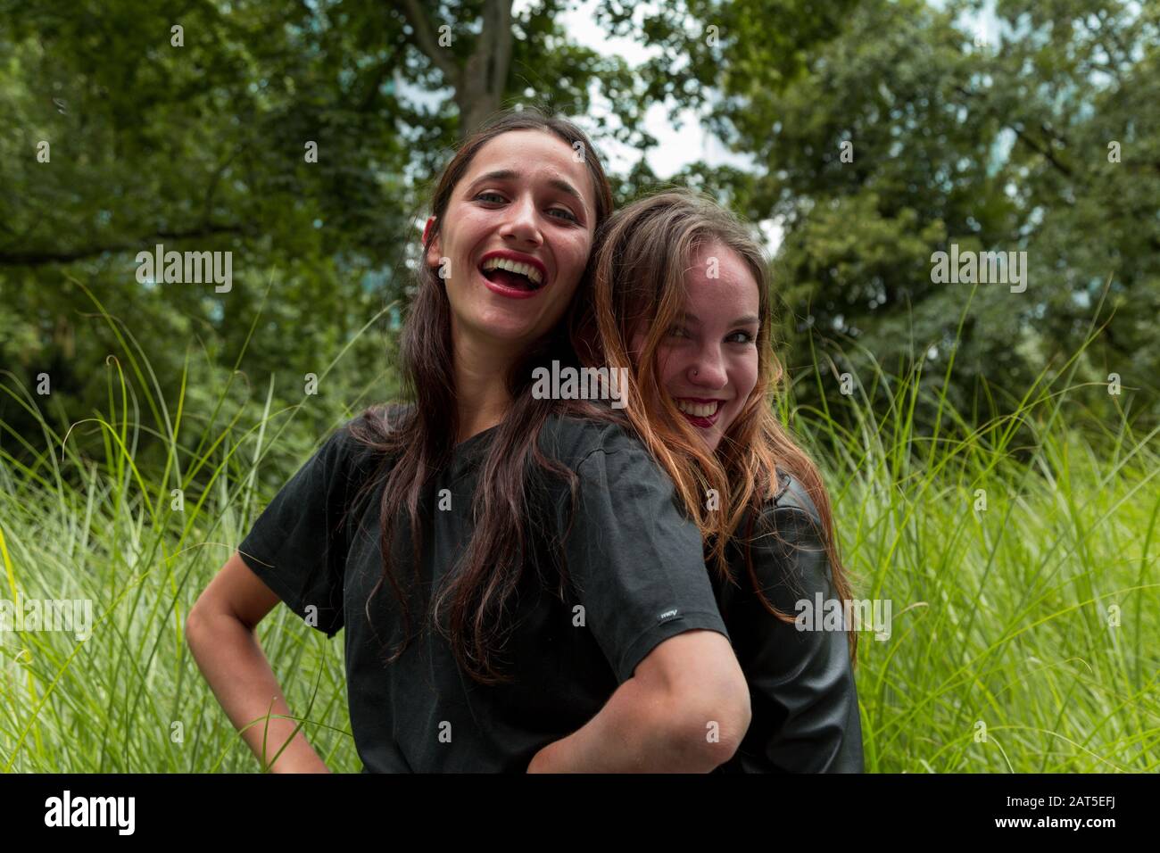 Portrait of two pretty young women of different races hugging and ...