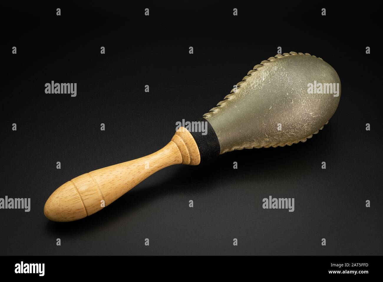 Closeup of a rawhide maracas lying on a black underground Stock Photo ...