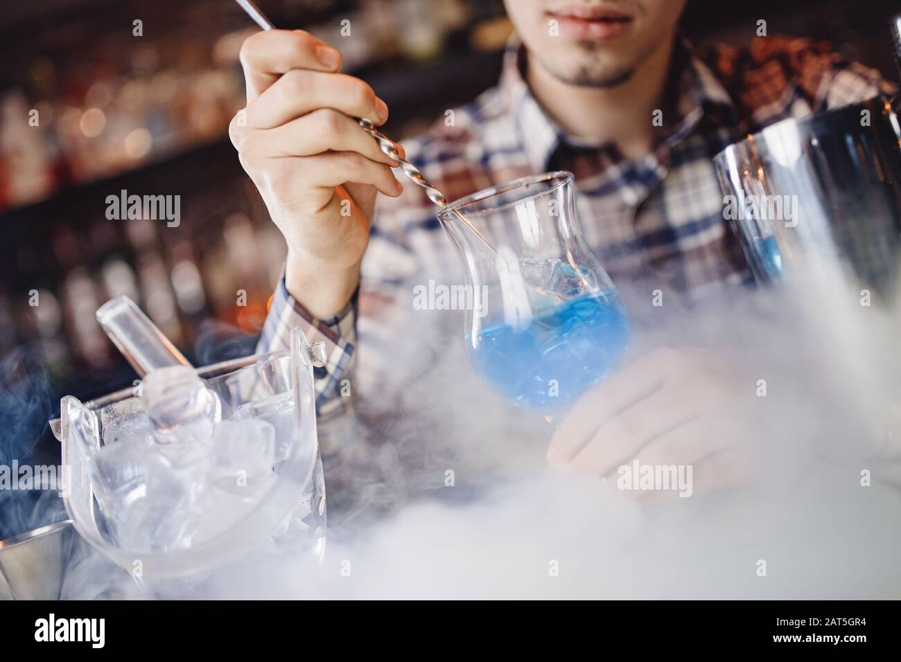 Barman mixes blue cocktail show with colorful alcoholic and smoke bar ...
