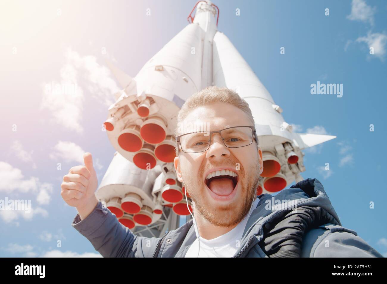 Happy tourist man taking selfie photo on background of rocket spaceport ...