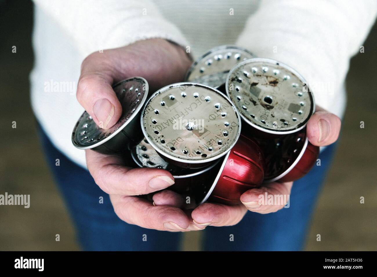 A woman holding a handful of used aluminum coffee pods or capsules from ...