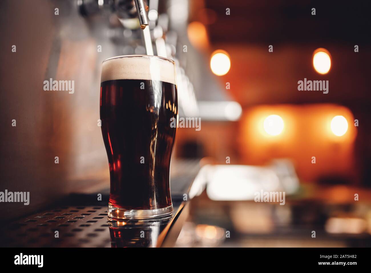 Dark Draft cold beer pour in glass from crane in pub Stock Photo - Alamy