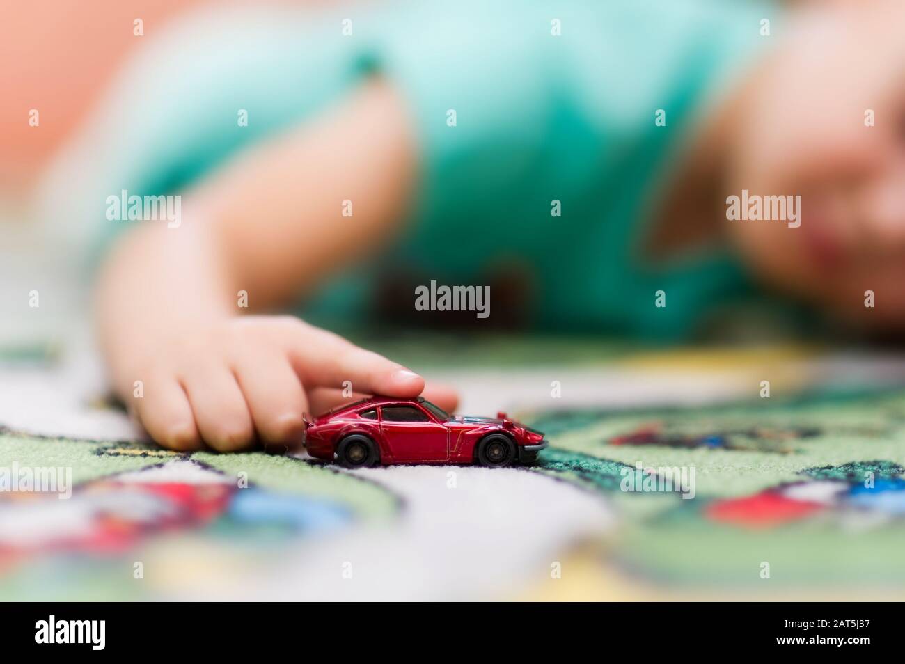 boy rolls a toy car on the floor close-up. Focus on hand and toy Stock ...