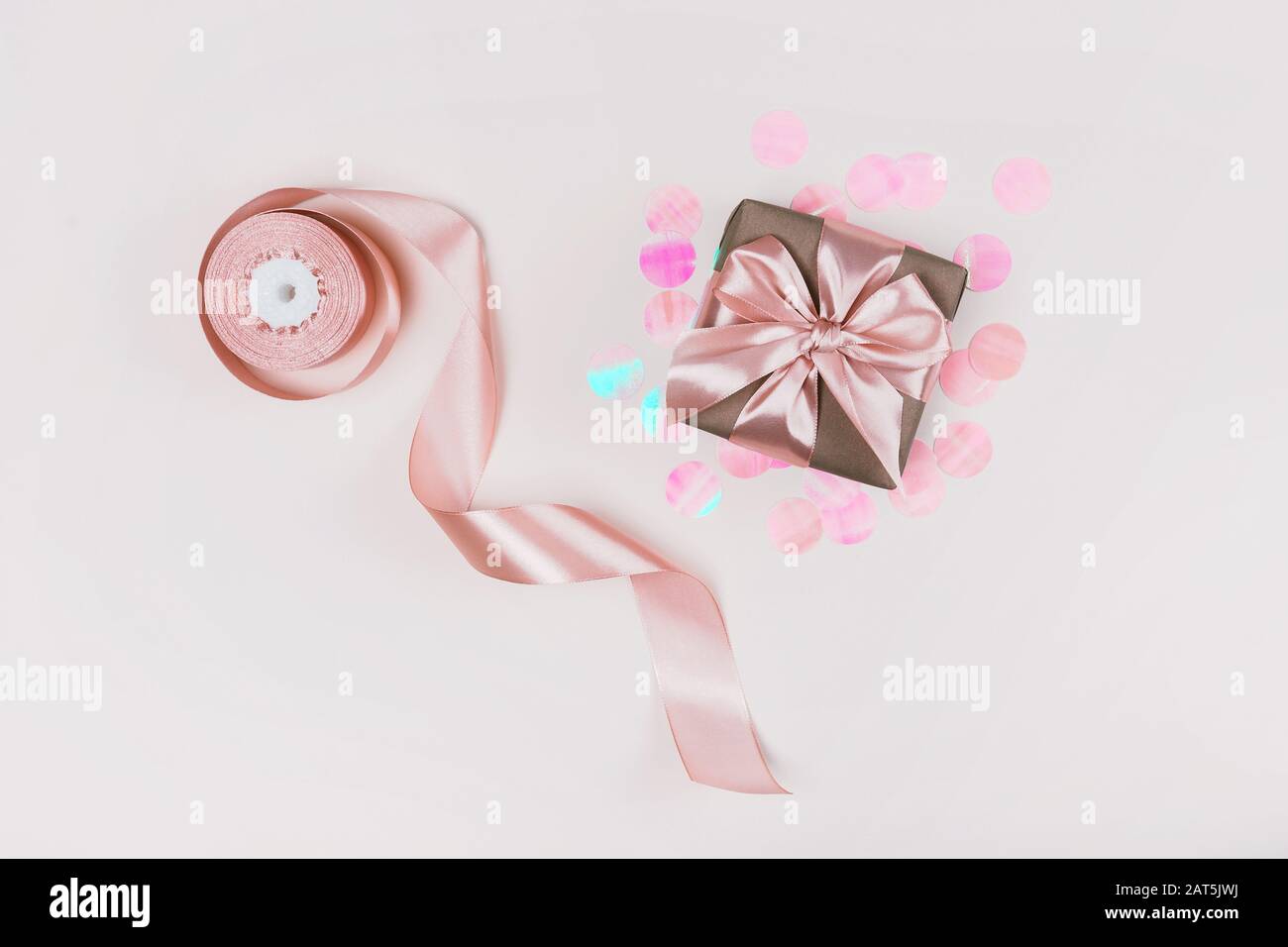 Gift box wrapped in craft paper with perfect pink ribbon on pale pink ...