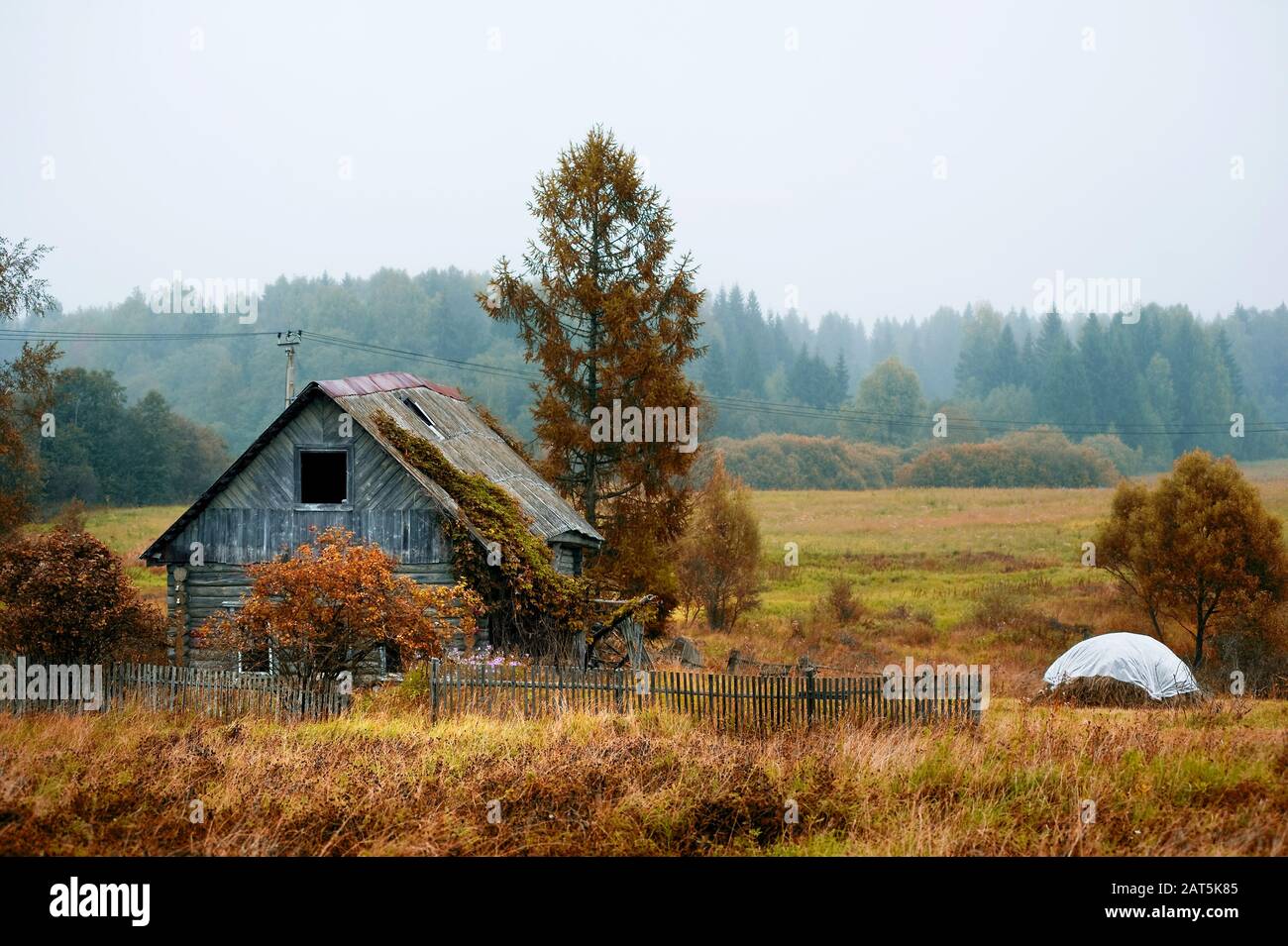 abandoned rickety house without windows with a partially missing fence ...