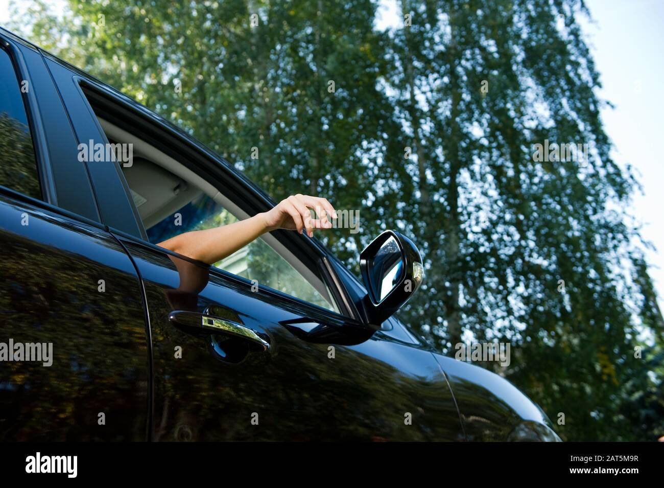 A young woman holds a relaxed arm outside the car - sticking her hand ...