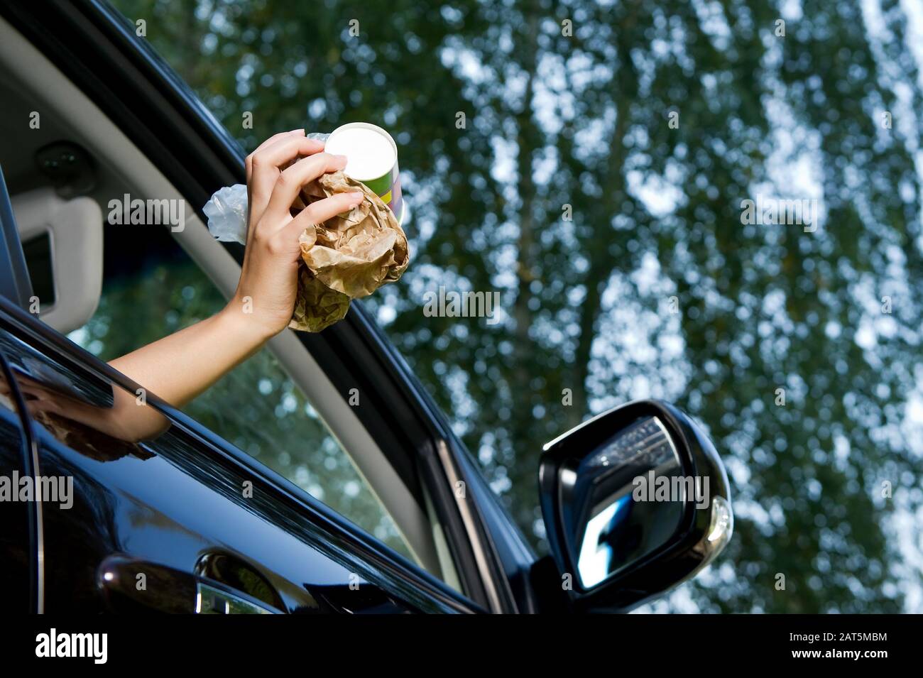 The girl is going to throw a handful of garbage accumulated in the car ...