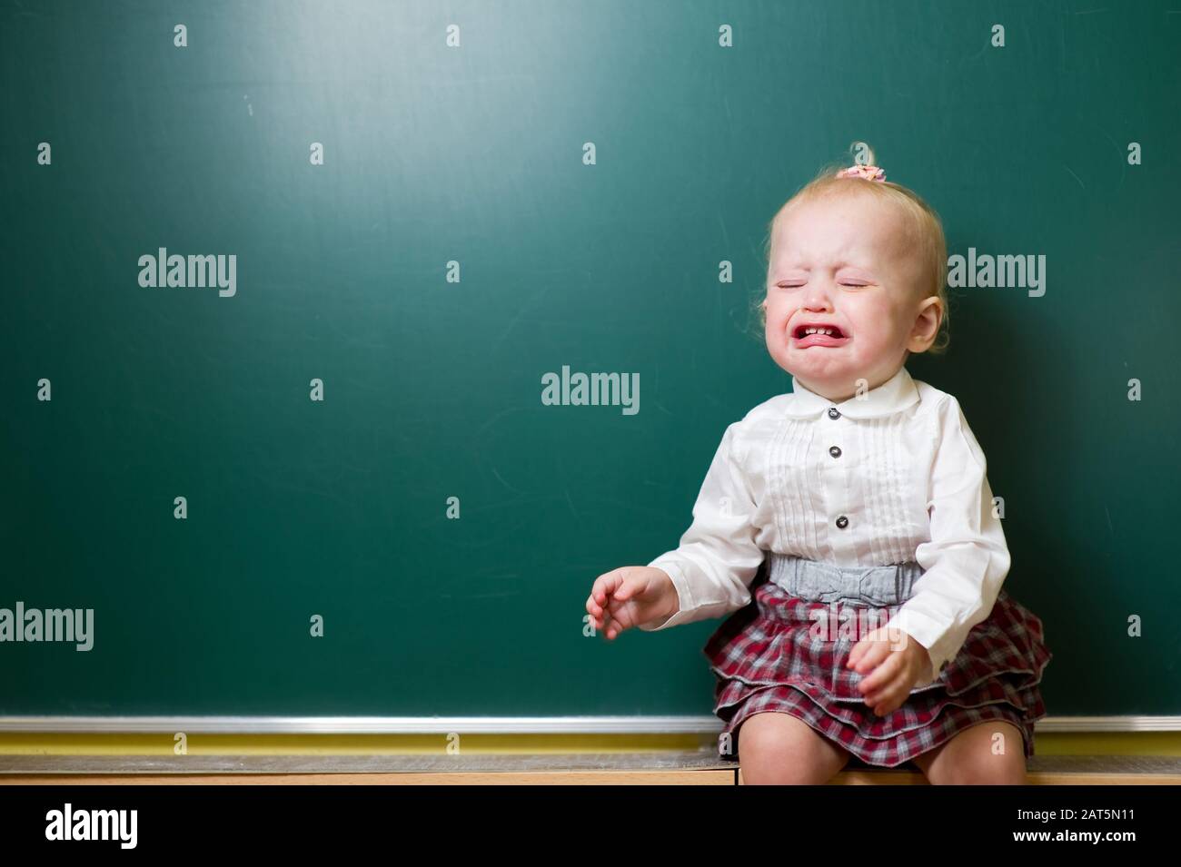 lbaby girl crying near a school blackboard. Crying baby on blackboard ...