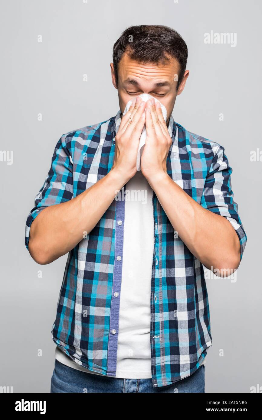 Young man sneeze his nose isolated on white background Stock Photo - Alamy