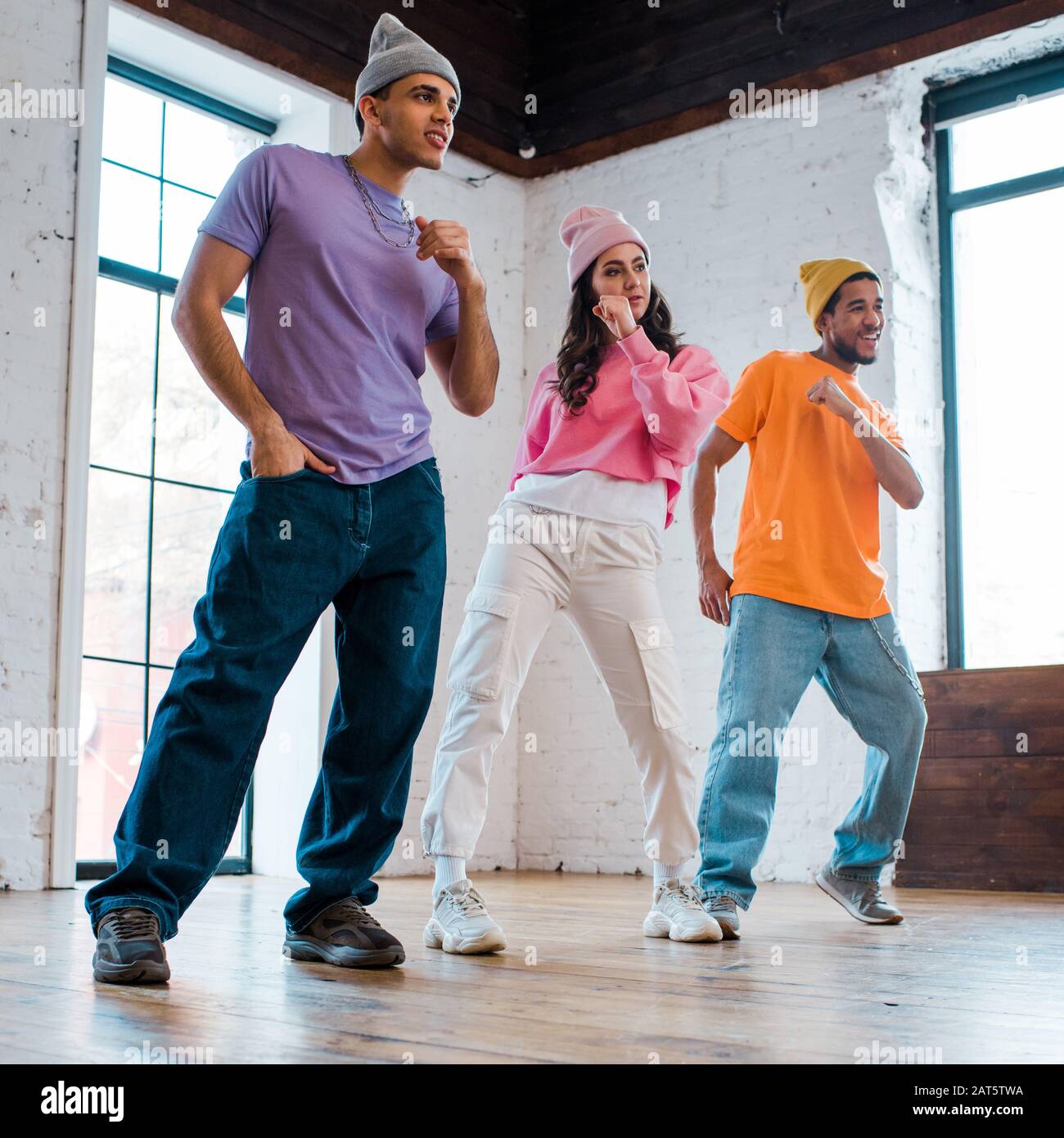 stylish multicultural men in hats breakdancing with beautiful girl ...