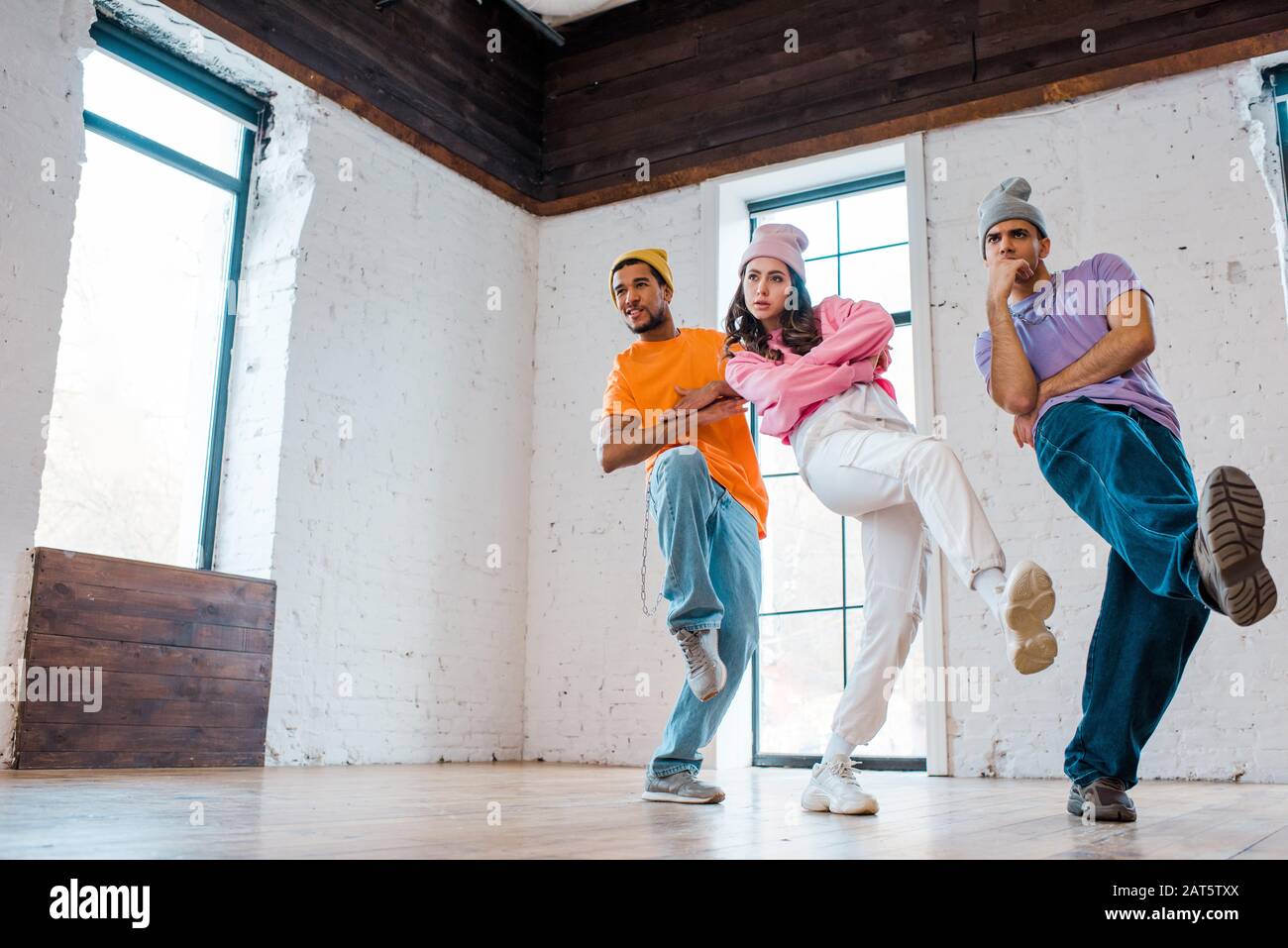 stylish girl with crossed arms breakdancing with multicultural men in ...