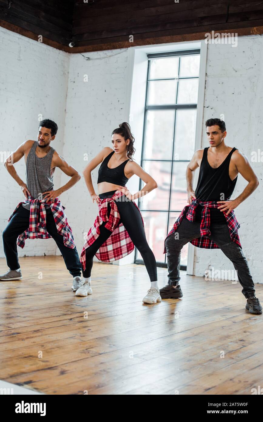 handsome multicultural men and attractive girl with hands on hips ...