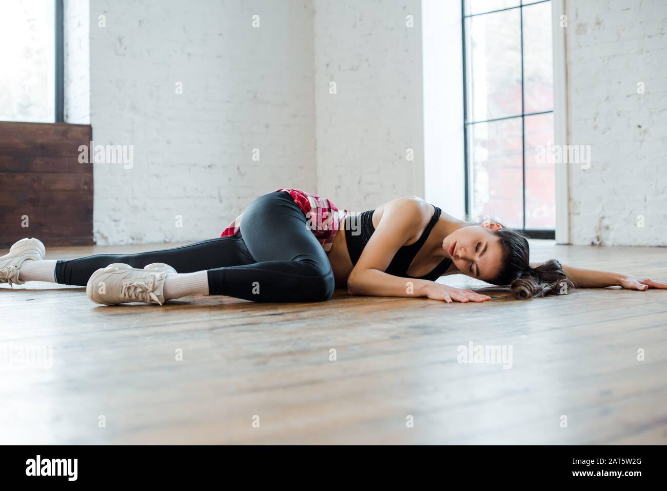 attractive girl lying on floor while dancing jazz funk in dance studio ...