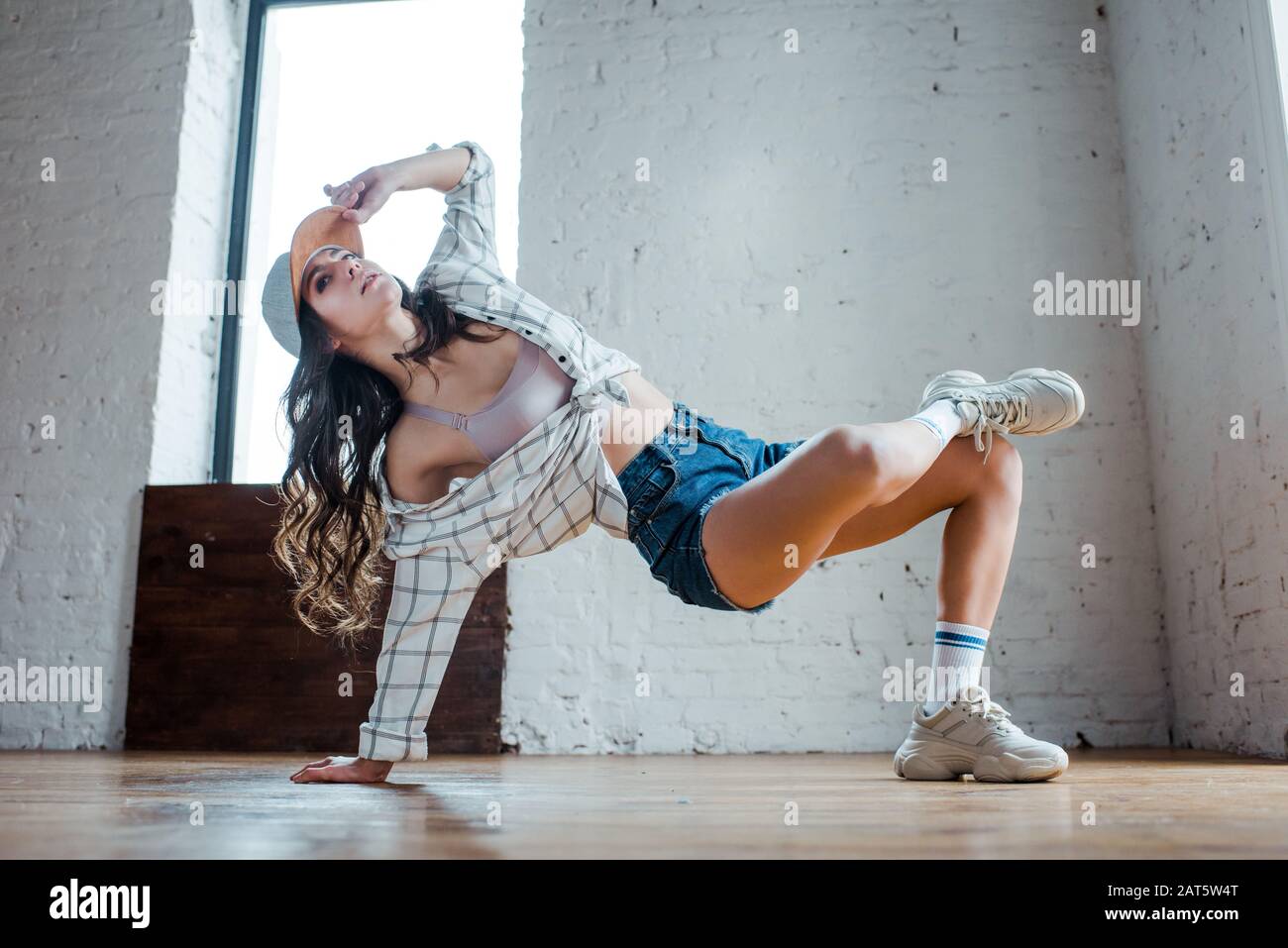 flexible girl touching cap and dancing hip-hop Stock Photo - Alamy