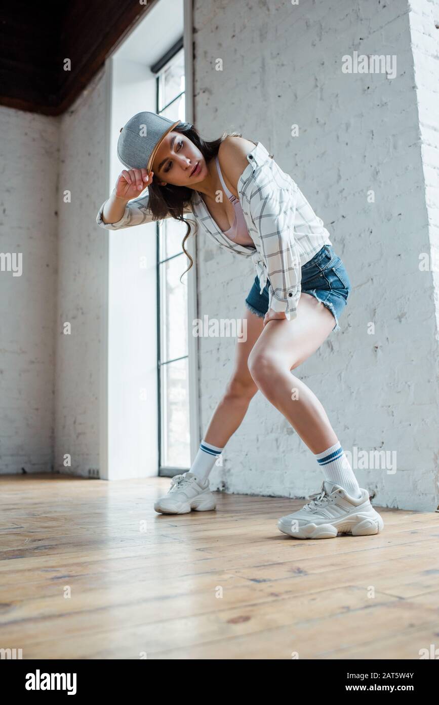 attractive dancer touching cap while dancing hip-hop Stock Photo - Alamy
