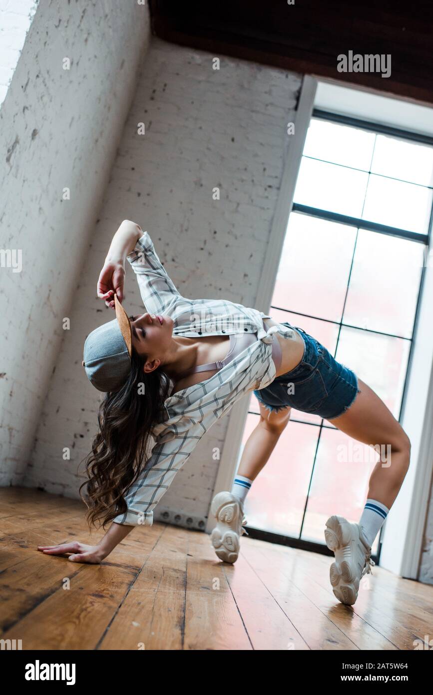 low angle view of beautiful dancer touching cap and dancing hip-hop in ...