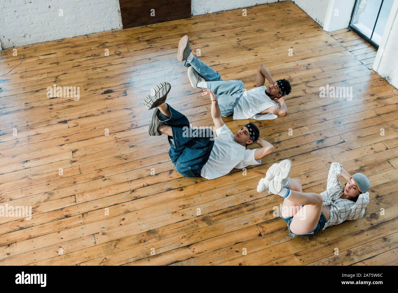 overhead view of trendy girl lying on floor with multicultural dancers ...