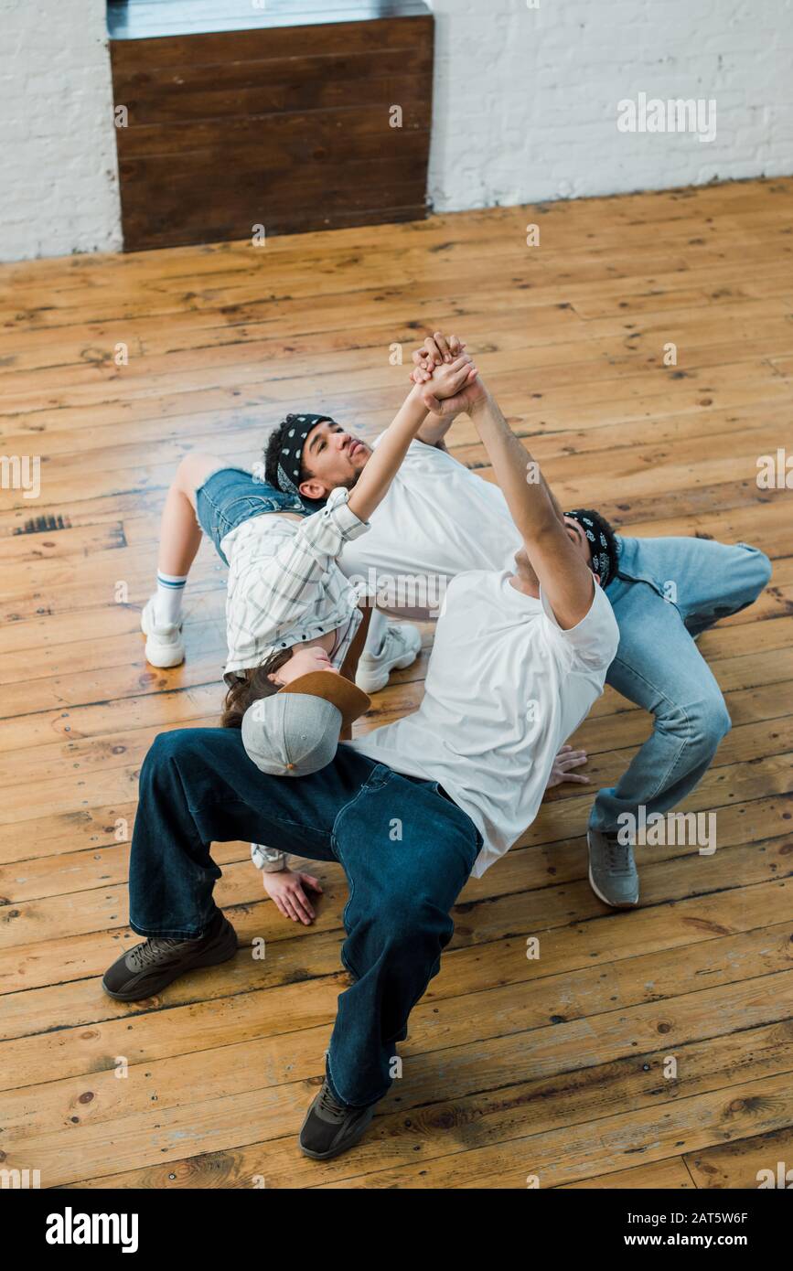overhead view of multicultural dancers holding hands while posing in ...