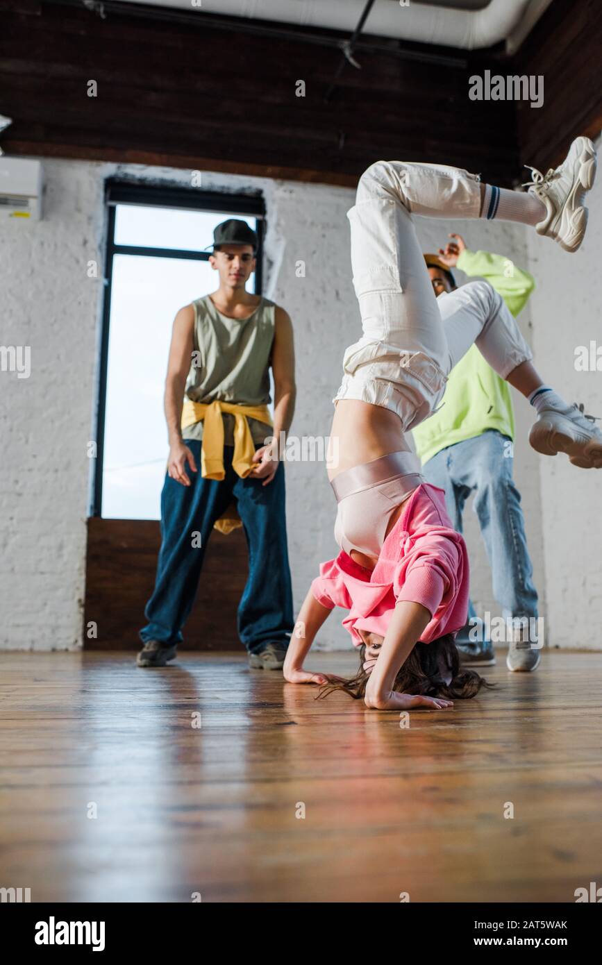selective focus of girl doing handstand while breakdancing near ...
