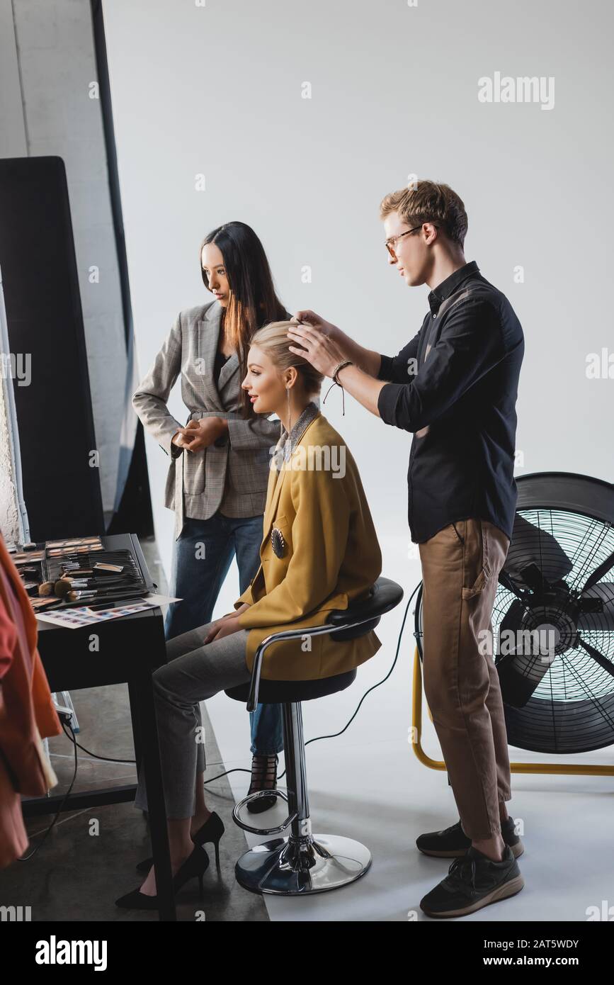 hairstylist doing hairstyle and model with producer looking away on ...