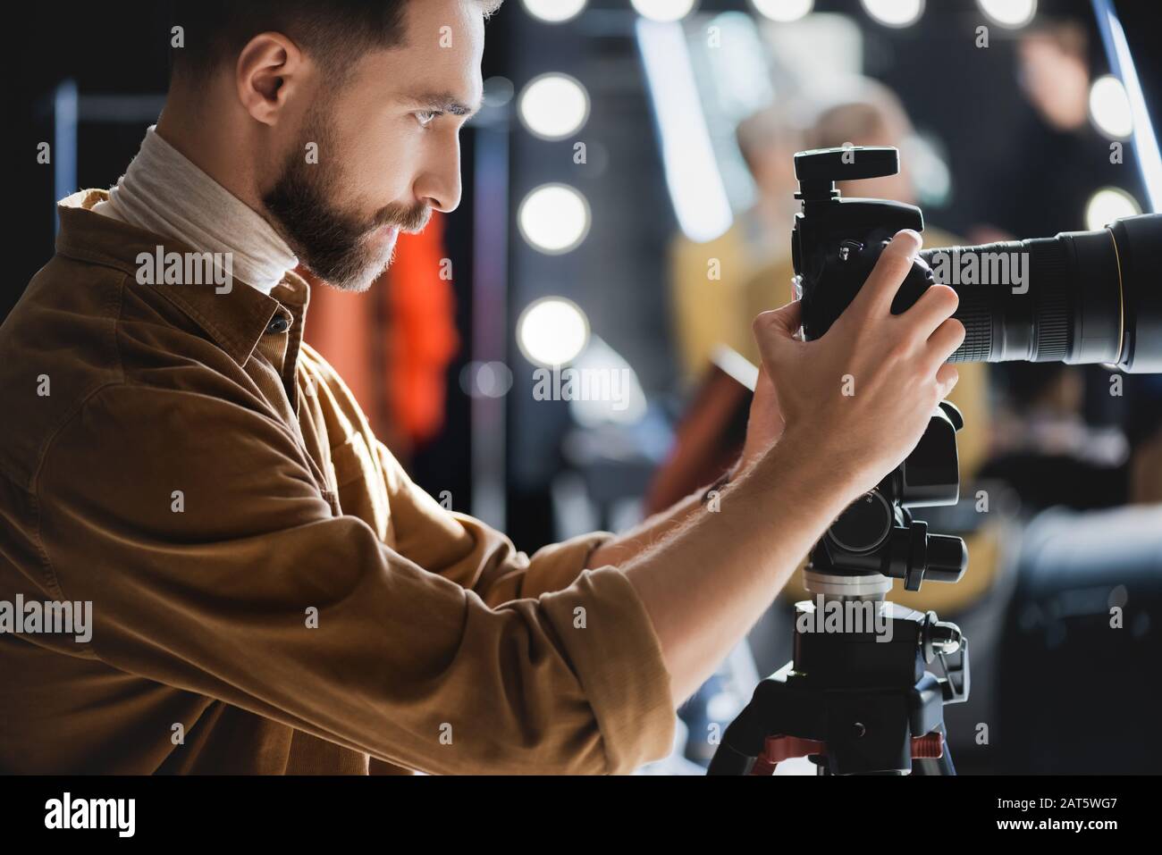 side view of photographer taking photo with digital camera on backstage ...